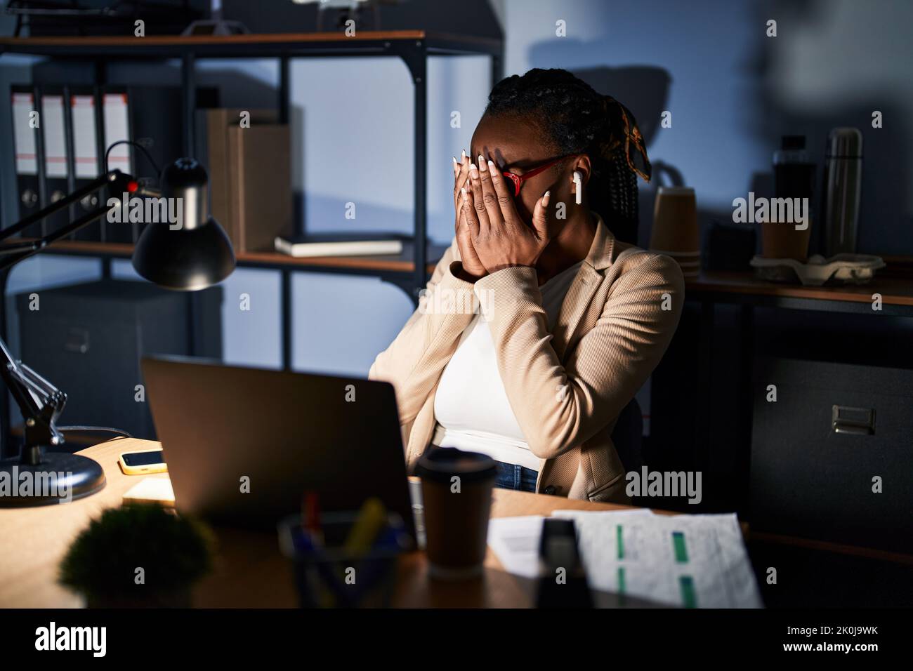 Beautiful black woman working at the office at night with sad ...