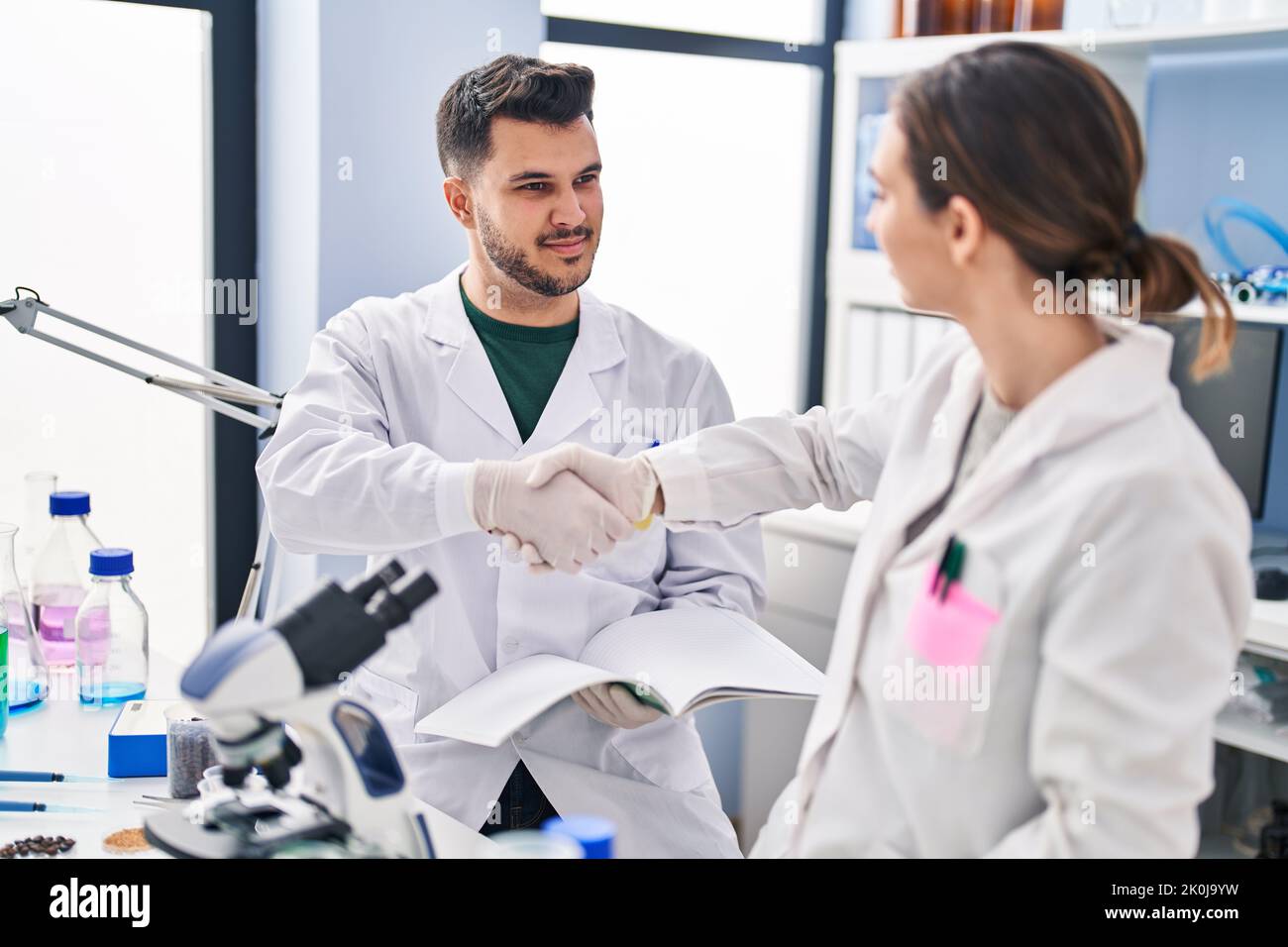 Man and woman wearing scientist uniform shake hands at laboratory Stock ...