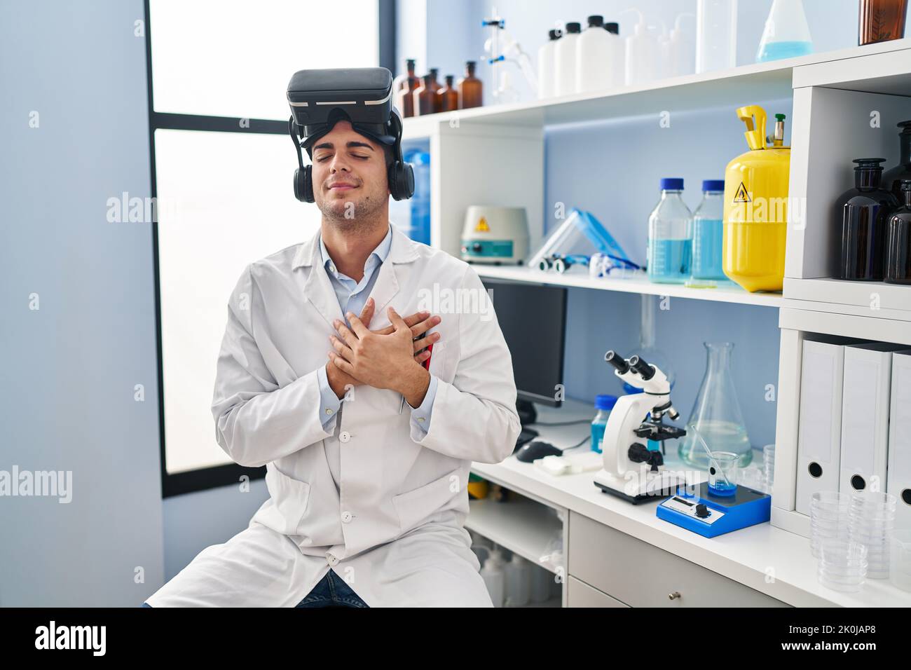 Young hispanic man working at scientist laboratory wearing vr glasses ...