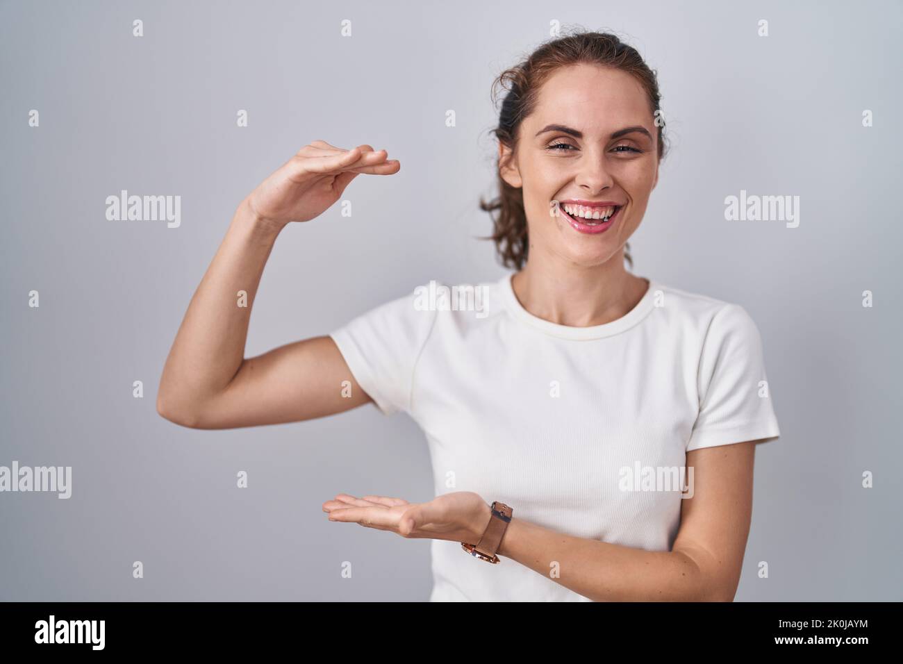 Beautiful brunette woman standing over isolated background gesturing ...