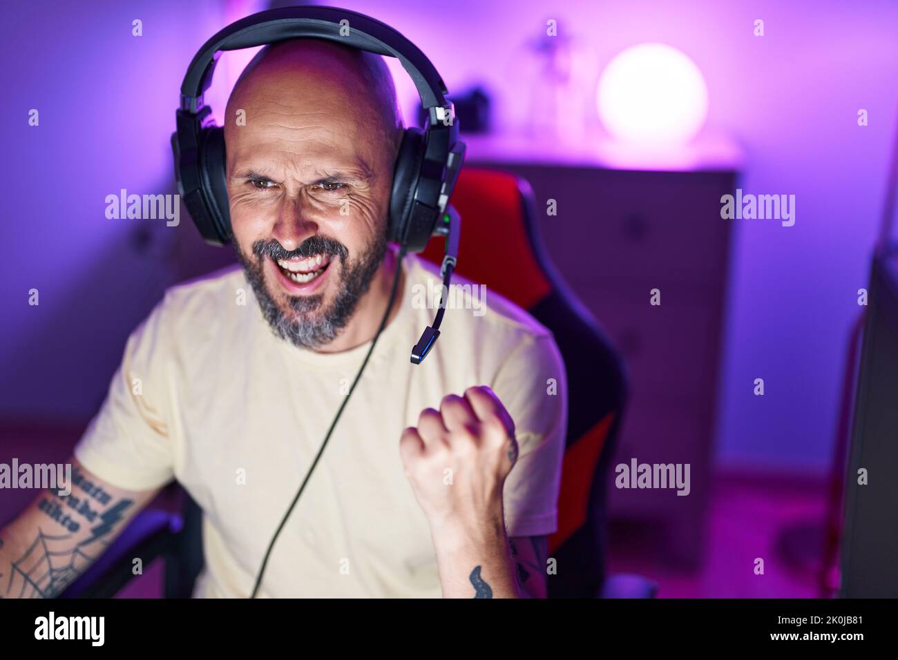 Young bald man streamer playing video game with winner expression at ...