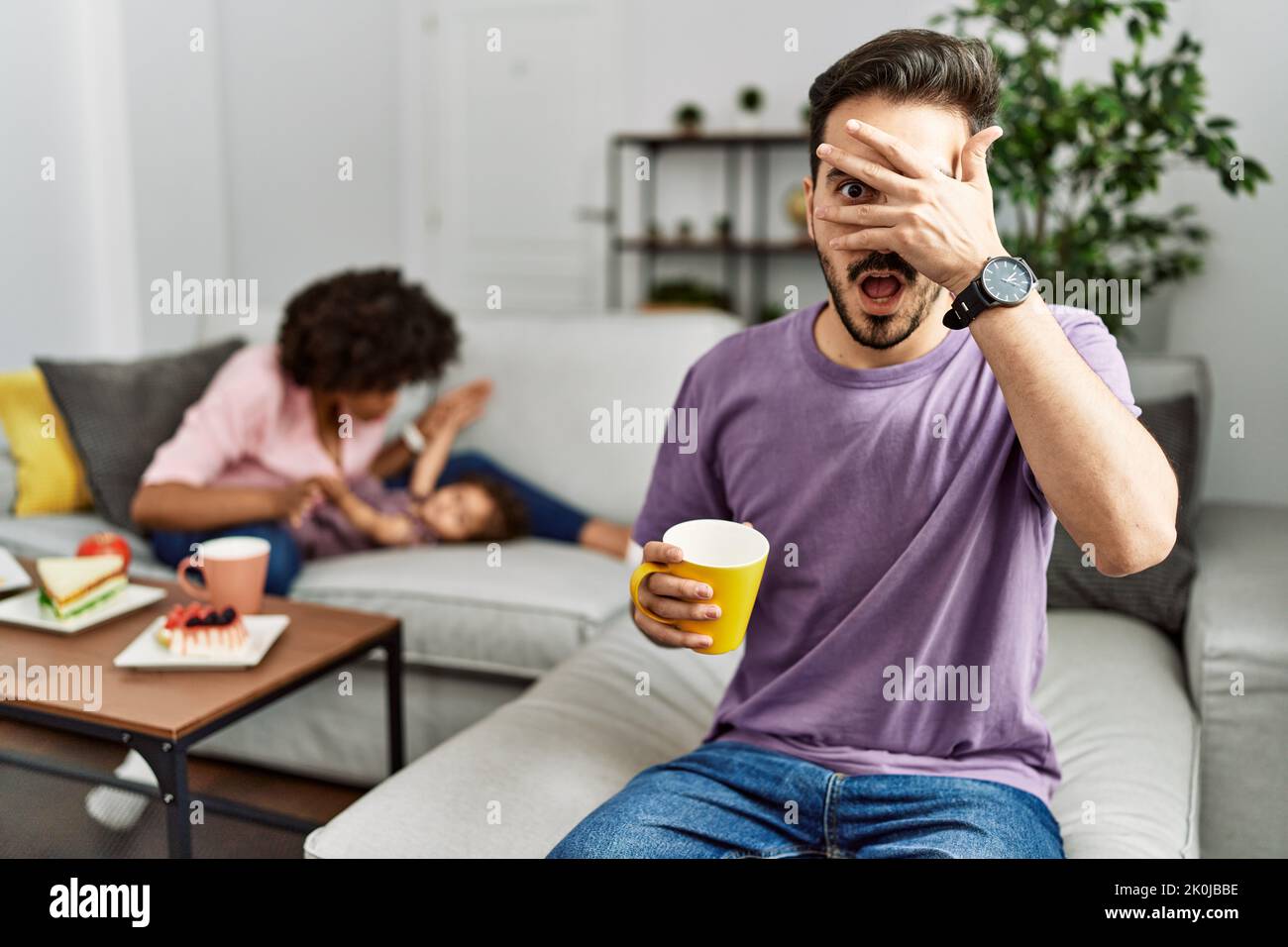 Hispanic father of interracial family drinking a cup coffee peeking in ...