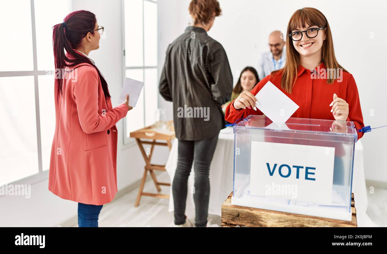 Young voter woman smiling happy putting vote in voting box at electoral ...