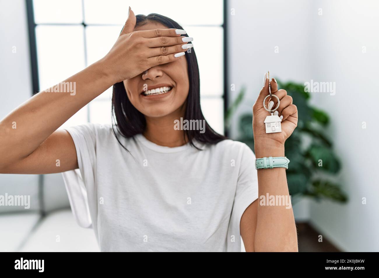 Young hispanic woman holding keys of new home smiling and laughing with ...