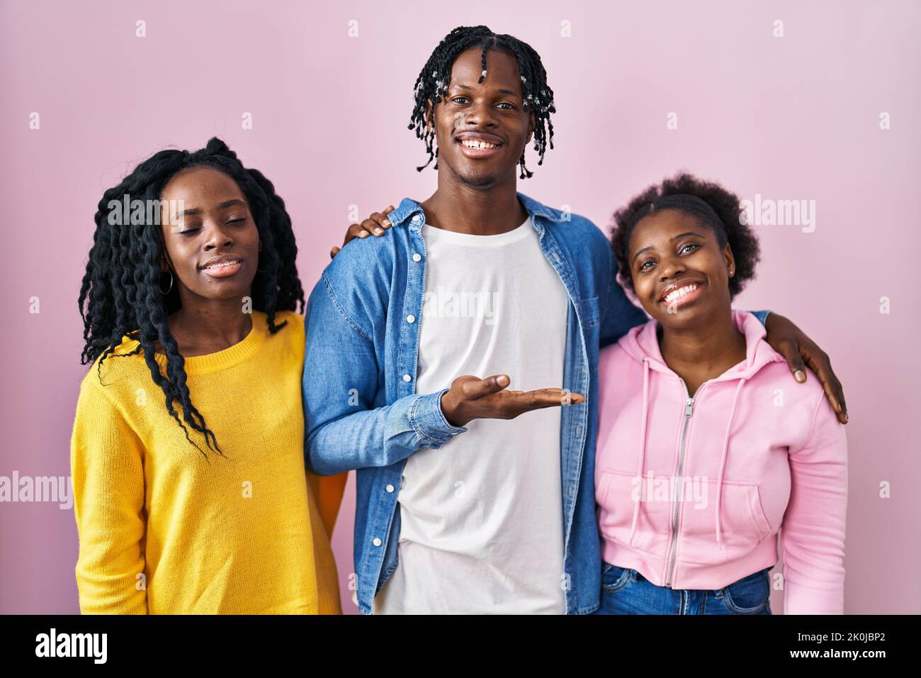 Group of three young black people standing together over pink ...