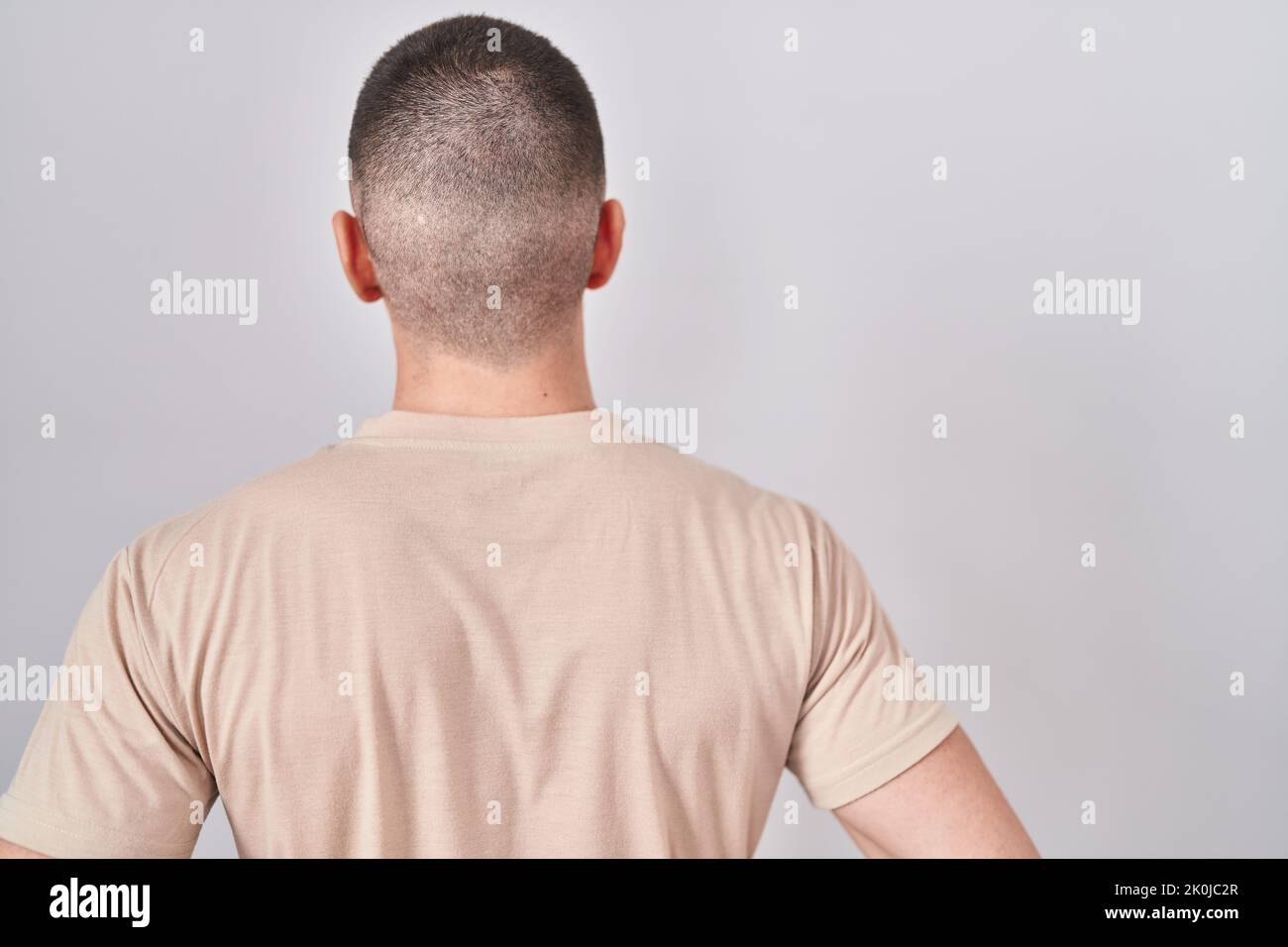 Young man standing over isolated background standing backwards looking ...