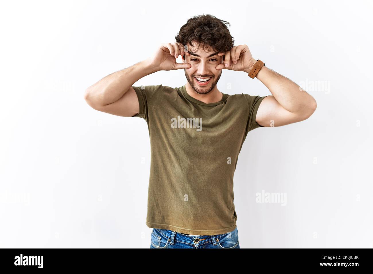 Hispanic man standing over isolated white background trying to open ...