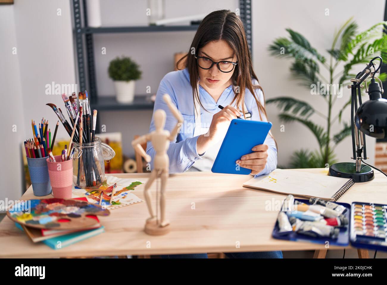 Young woman artist using touchpad drawing manikin on touchpad at art ...