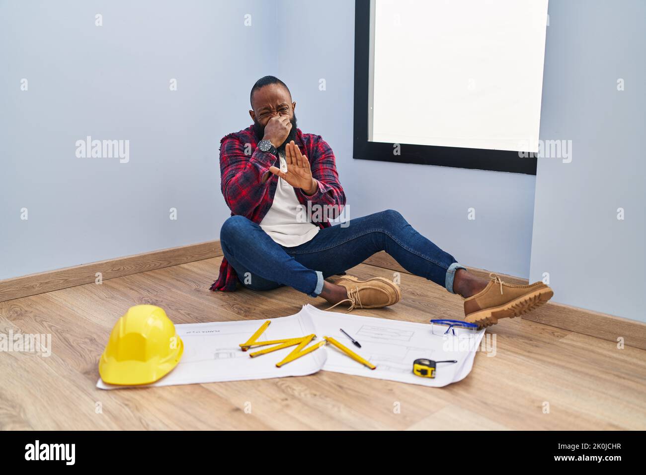 African american man sitting on the floor at new home looking at ...