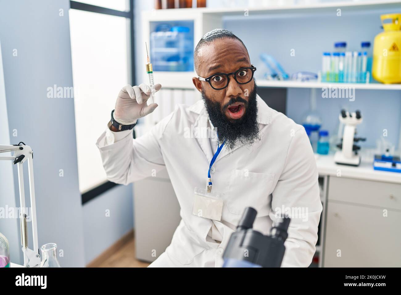 African american man working at scientist laboratory holding syringe ...