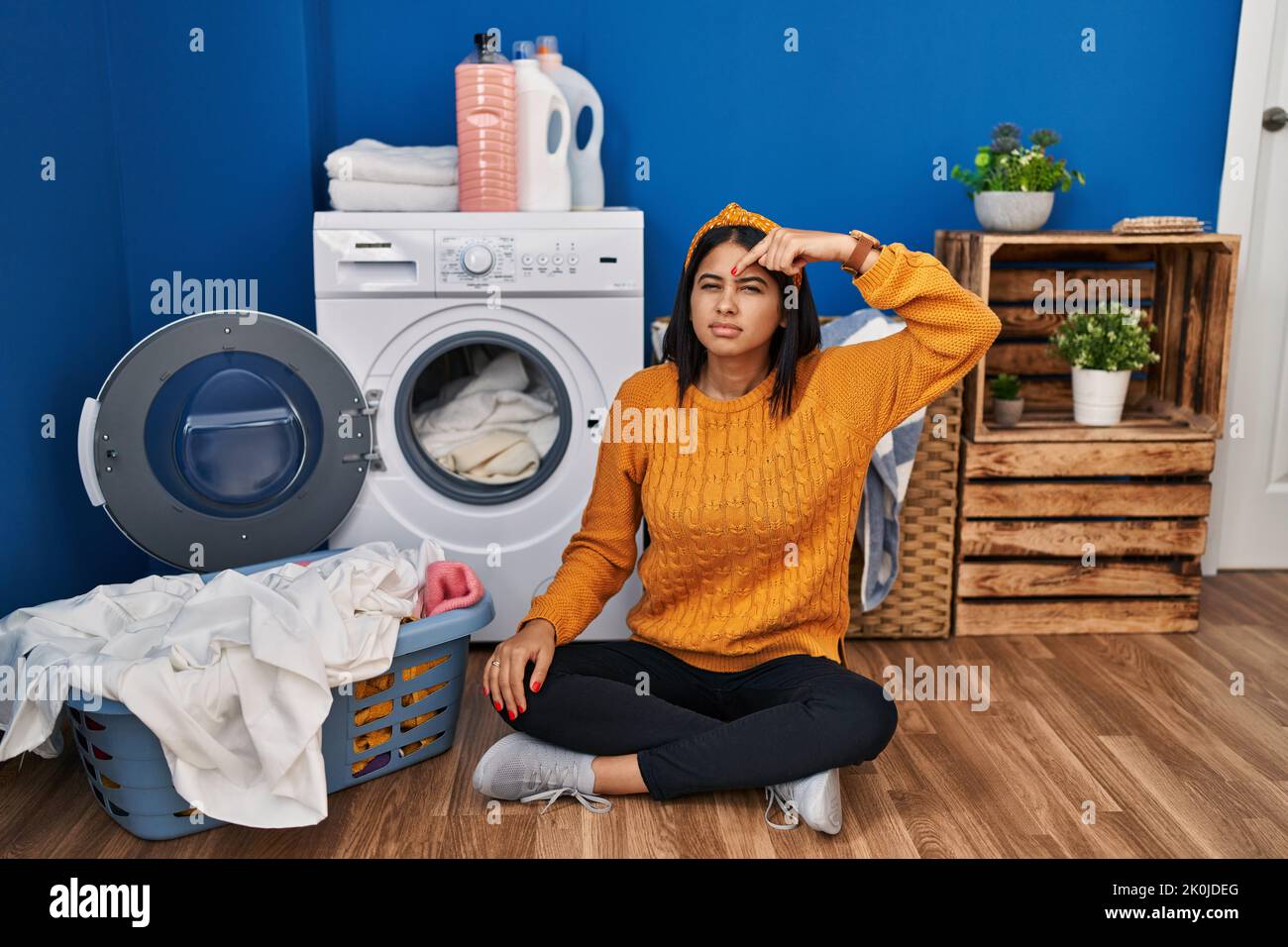 Young hispanic woman doing laundry pointing unhappy to pimple on ...