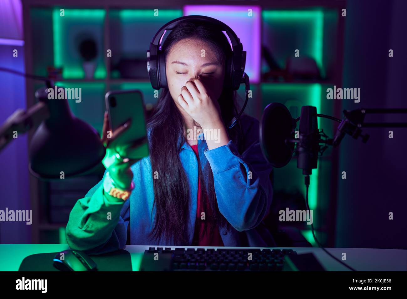 Young asian woman playing video games with smartphone tired rubbing ...