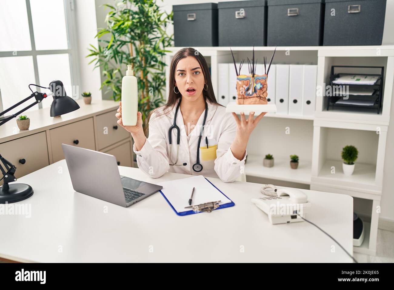 Hispanic doctor woman holding model of human anatomical skin and hair ...