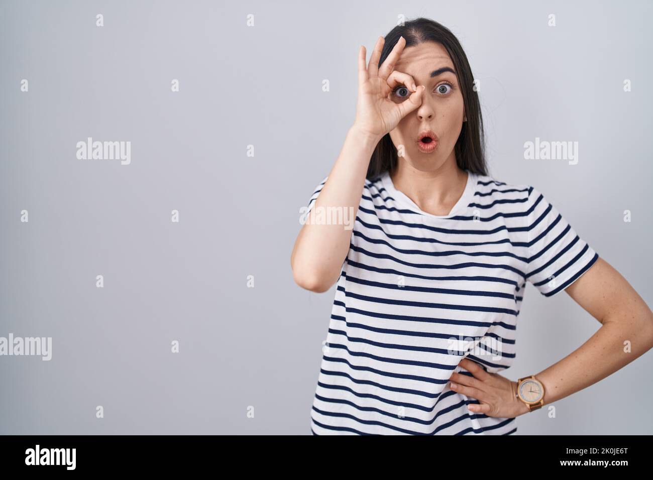Young brunette woman wearing striped t shirt doing ok gesture shocked ...