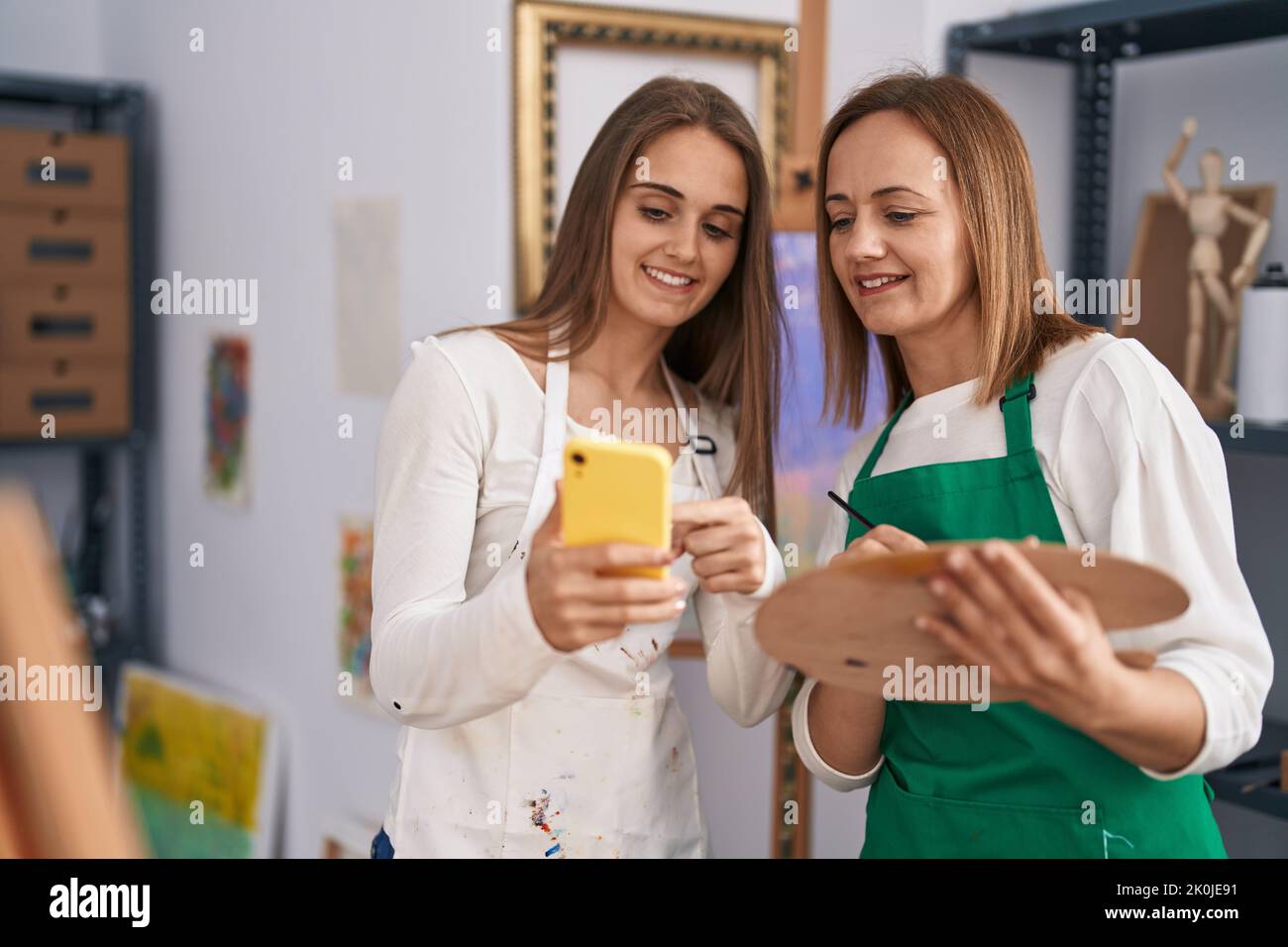 Two women artists smiling confident using smartphone drawing at art ...