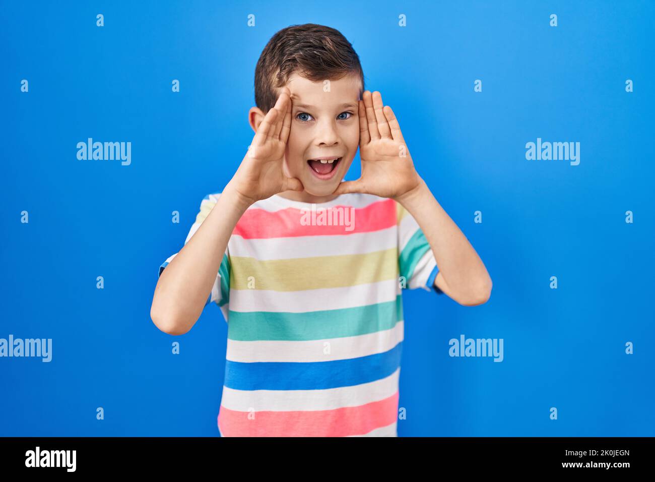 Young caucasian kid standing over blue background smiling cheerful ...