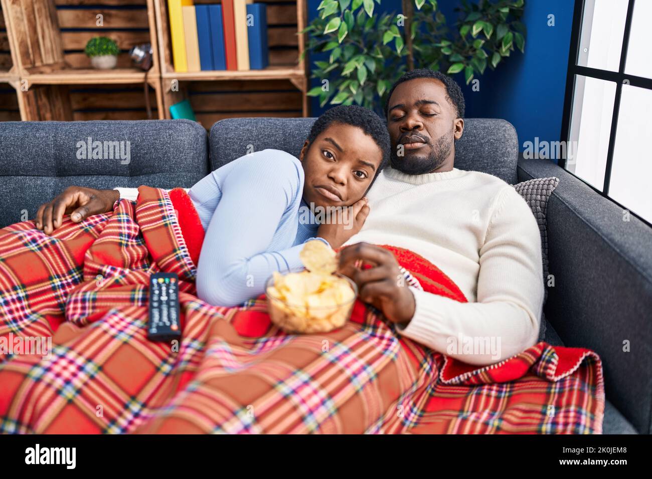 Young african american couple sitting on the sofa watching tv depressed ...