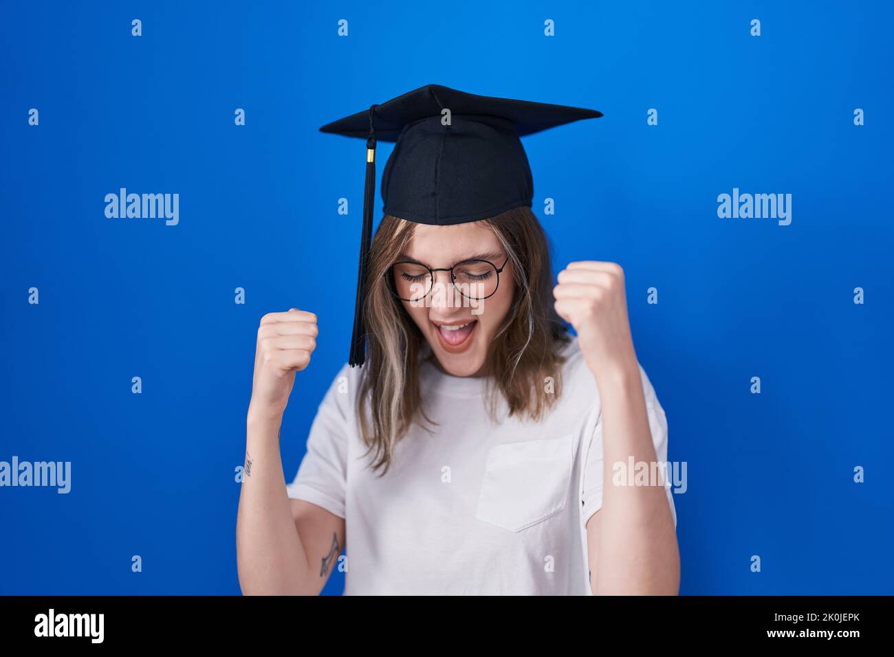 Blonde caucasian woman wearing graduation cap very happy and excited ...