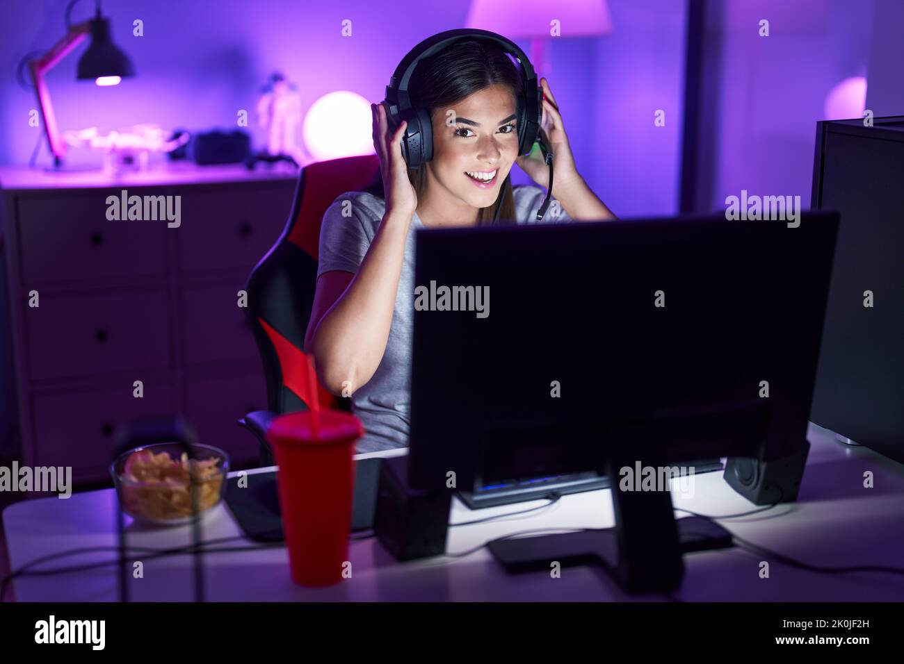 Young beautiful hispanic woman streamer playing video game at gaming ...