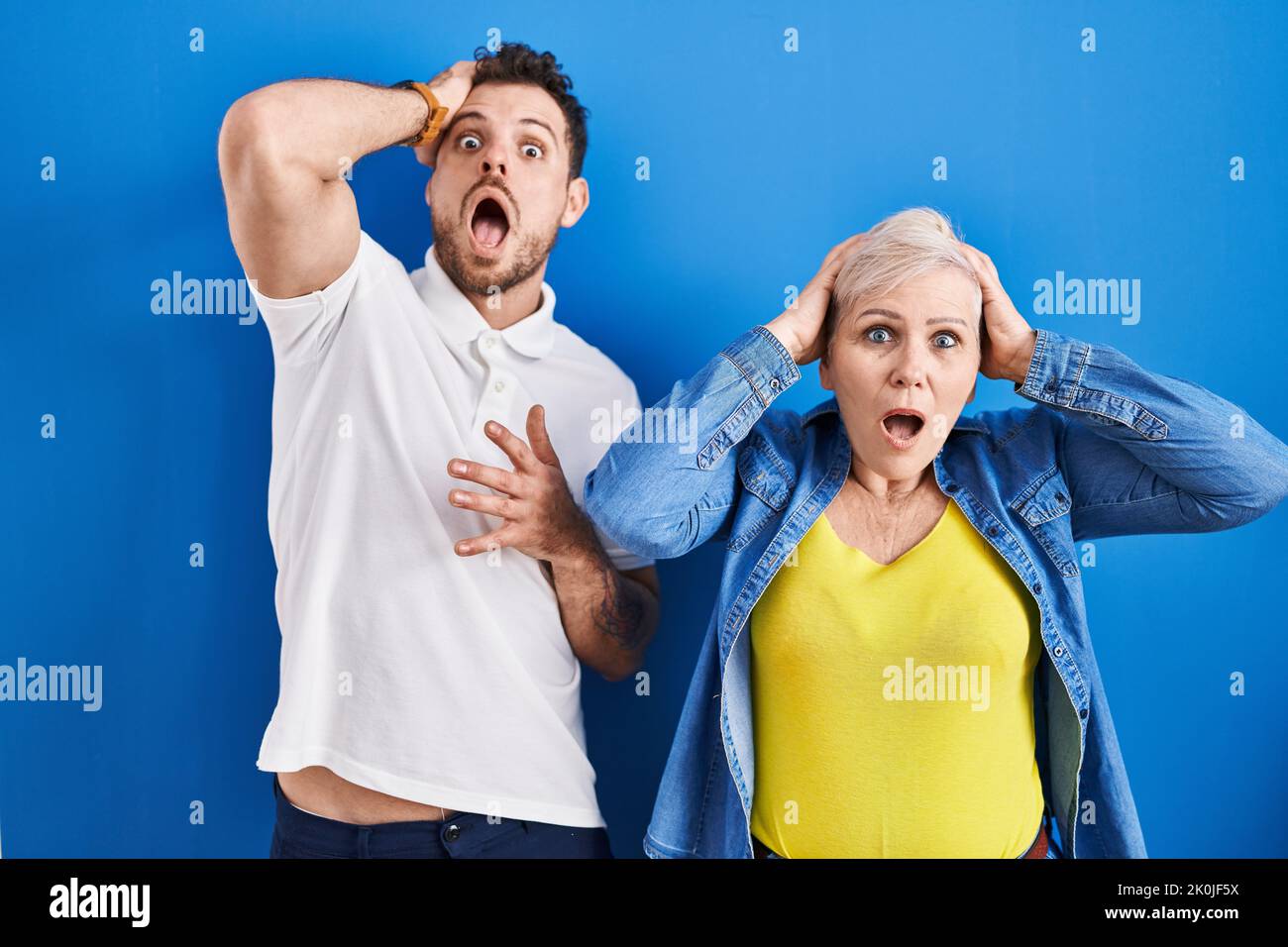 Young brazilian mother and son standing over blue background crazy and ...