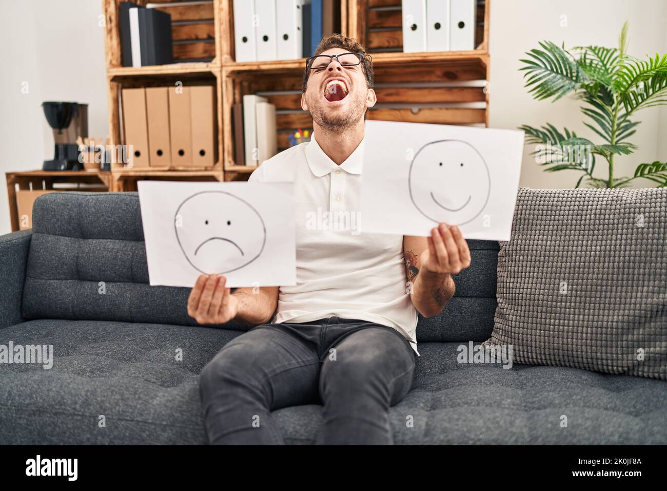 Young hispanic man working on depression holding sad to happy emotion ...