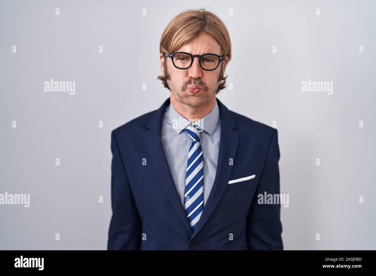 Caucasian man with mustache wearing business clothes puffing cheeks ...