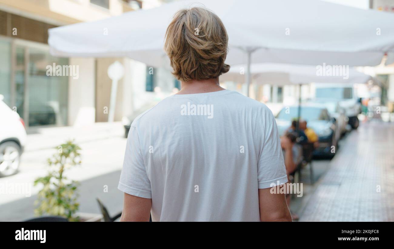 Young blond man standing on back view at street Stock Photo - Alamy