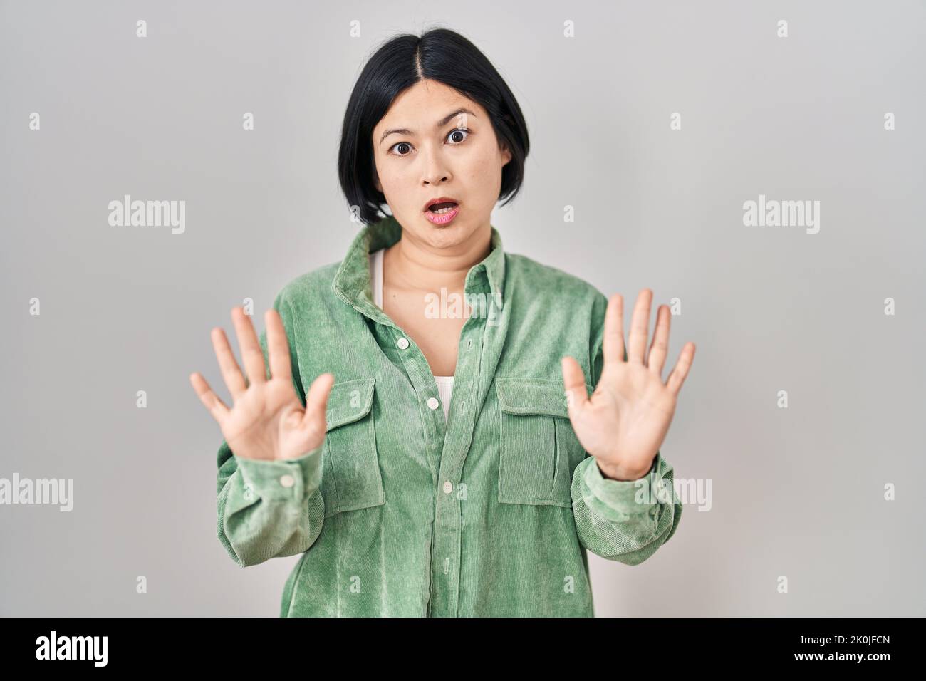 Young asian woman standing over white background moving away hands ...
