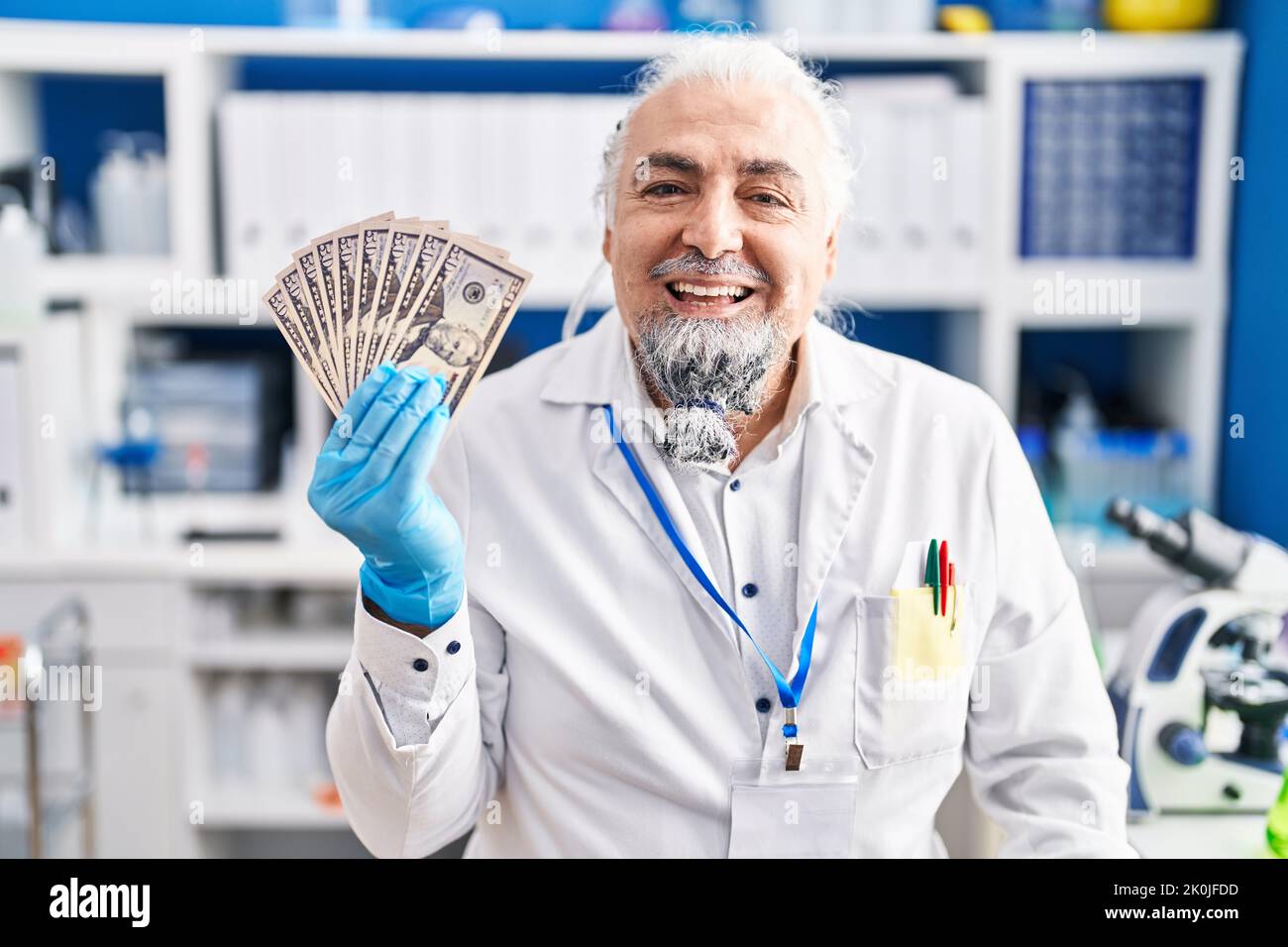 Middle age man with grey hair working at scientist laboratory holding ...