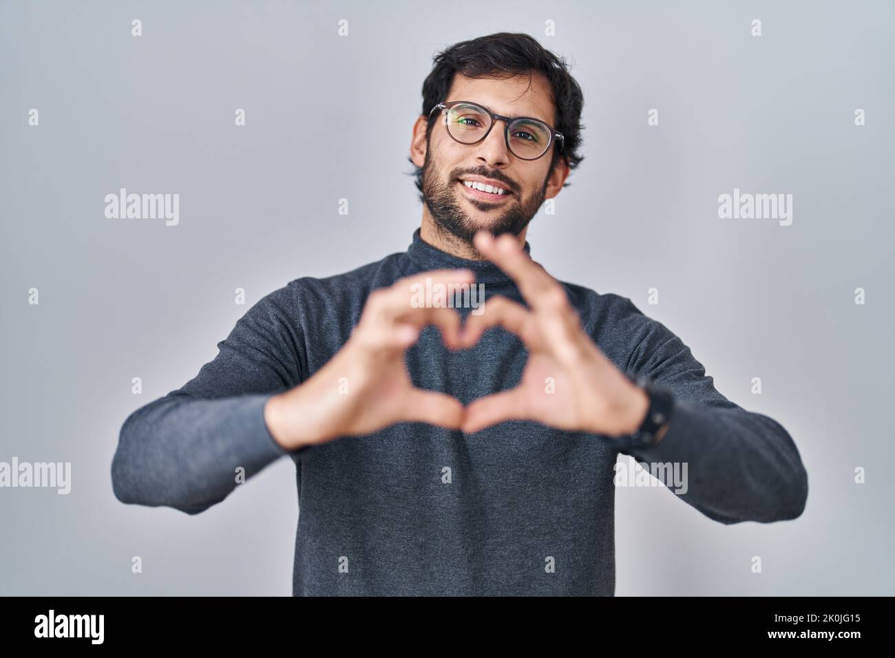 Handsome latin man standing over isolated background smiling in love ...