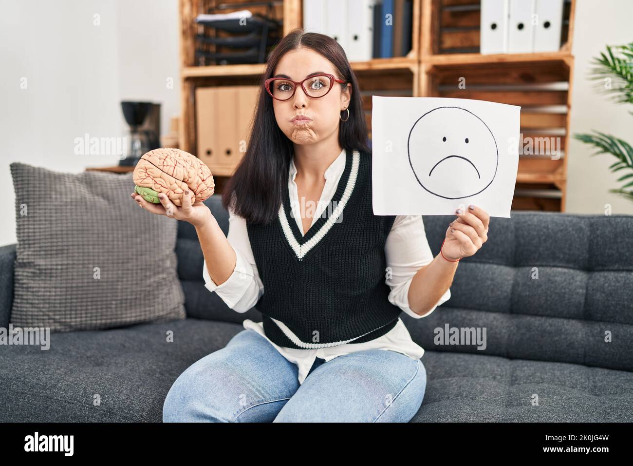 Young hispanic woman working on depression holding sad emotion paper ...
