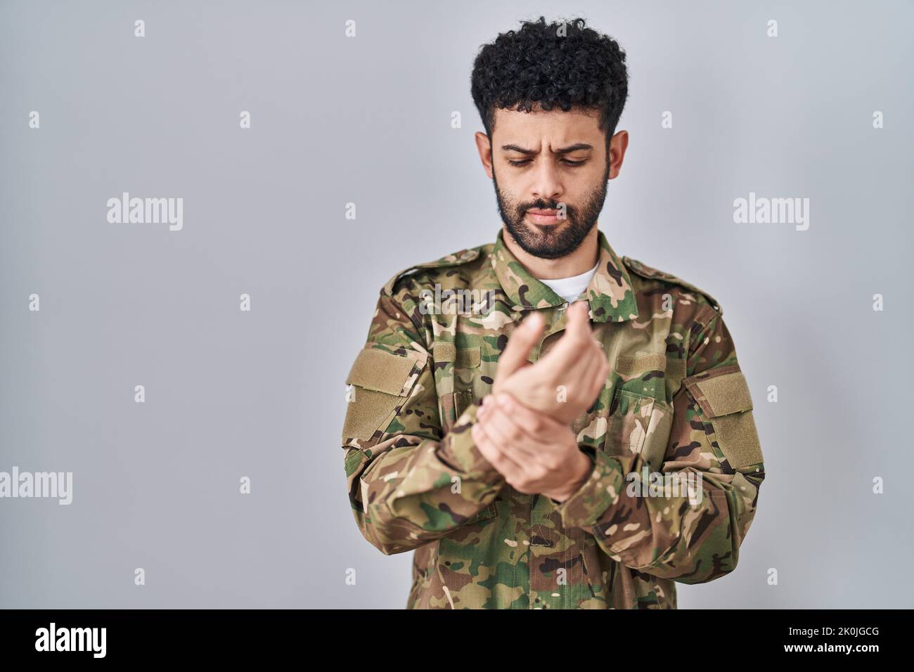 Arab man wearing camouflage army uniform suffering pain on hands and ...