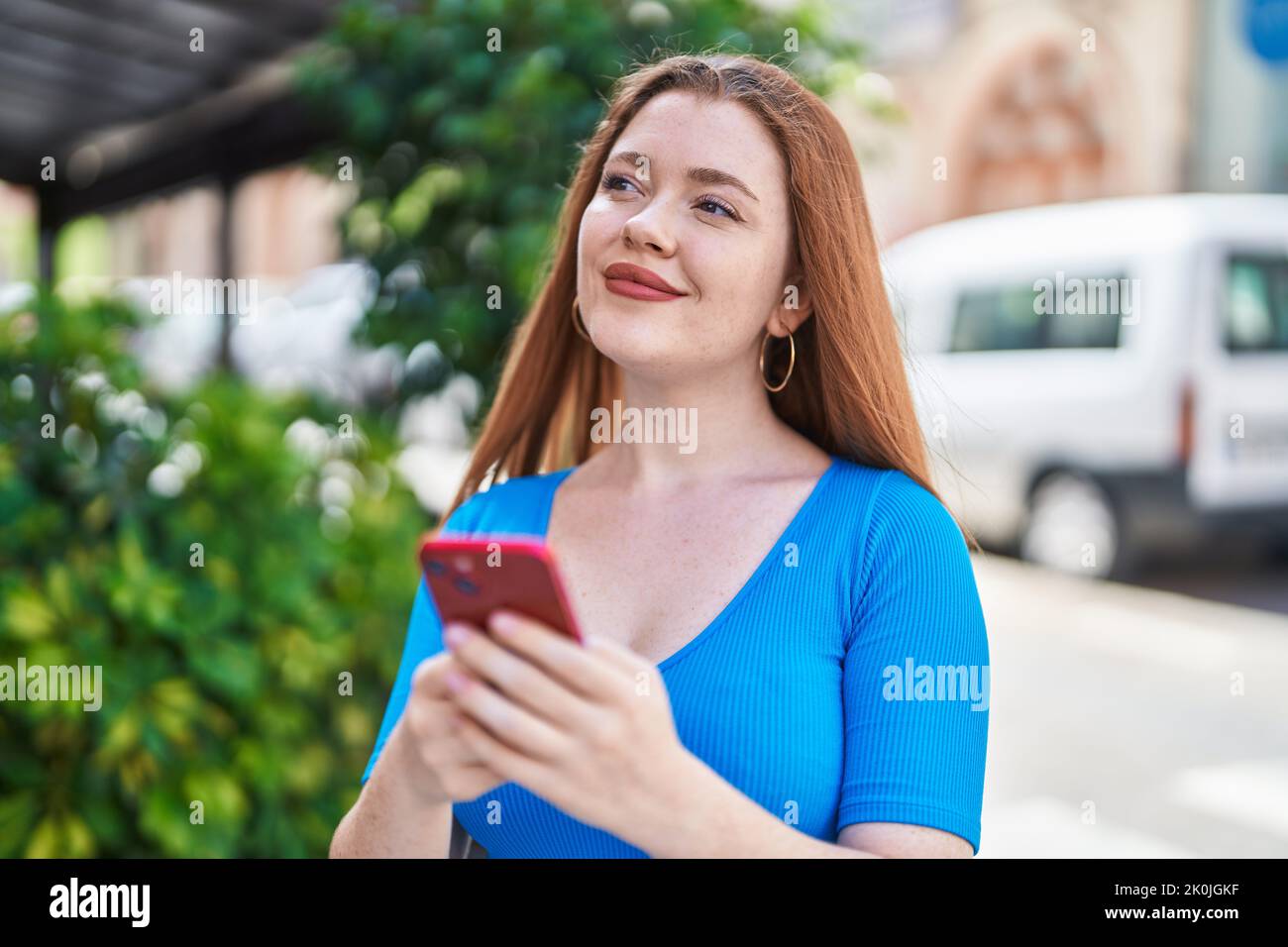 Young redhead woman smiling confident using smartphone at street Stock ...