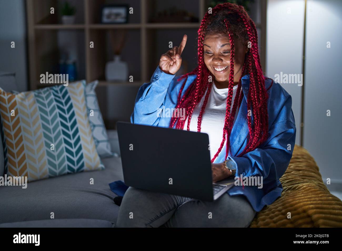 African american woman with braided hair using computer laptop at night ...