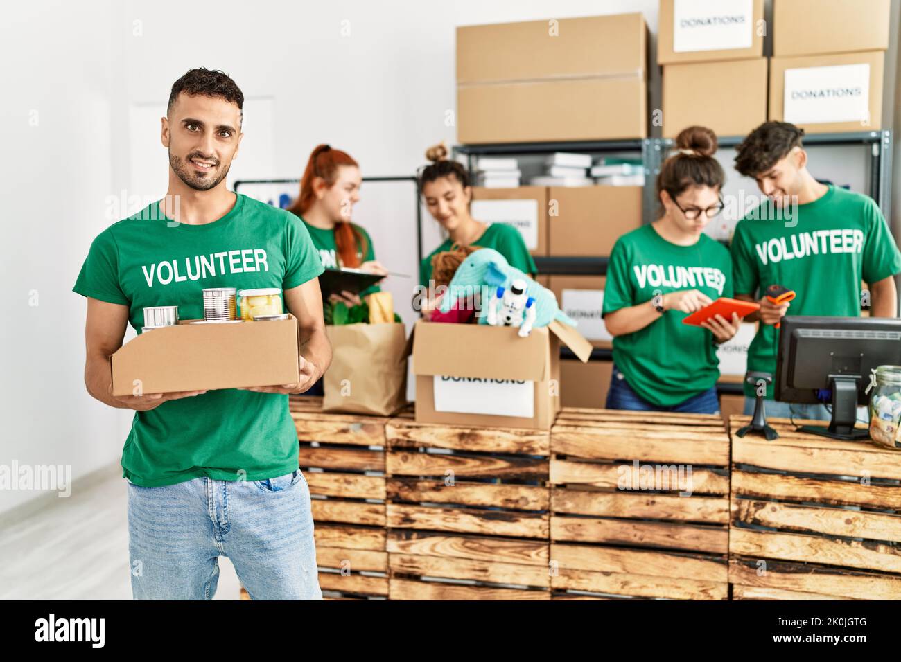 Group of young volunteers working at charity center. Man smiling happy ...