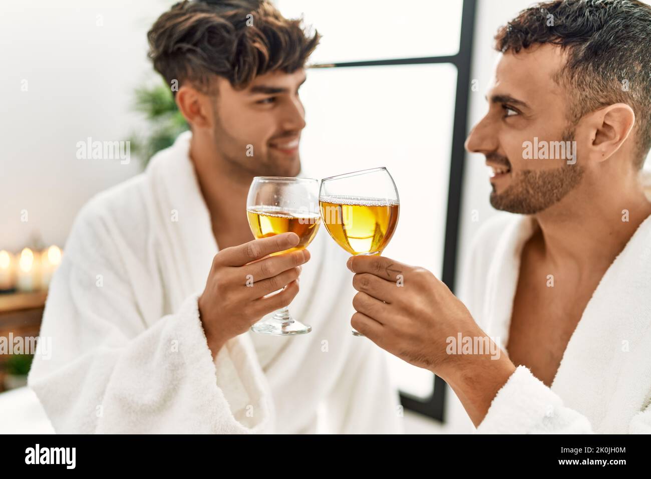 Two hispanic men couple toasting with champagne sitting on massage ...