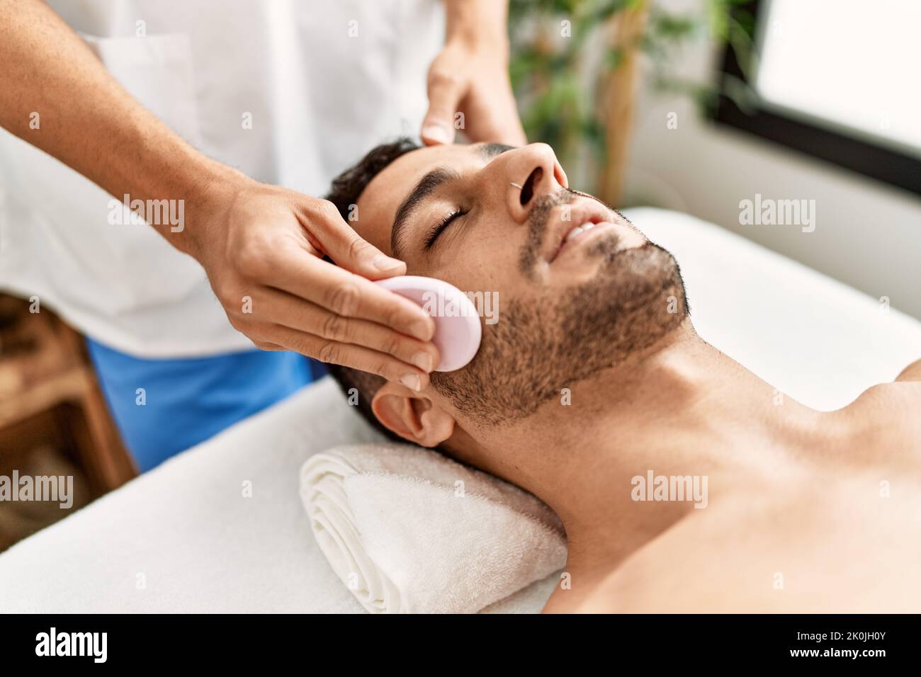 Two hispanic men therapist and patient having facial treatment cleaning ...
