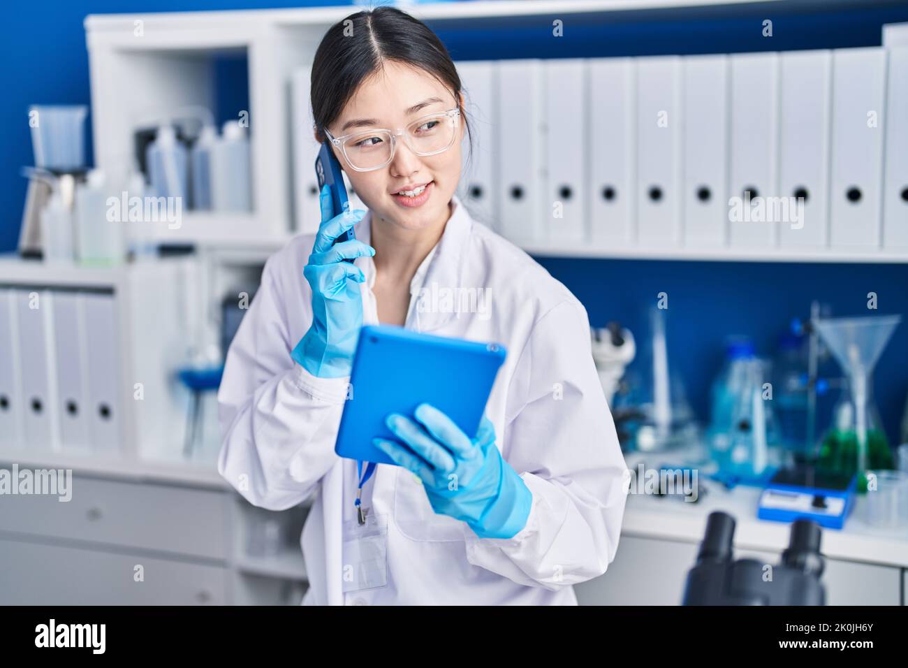 Chinese woman scientist using touchpad talking on smartphone at ...