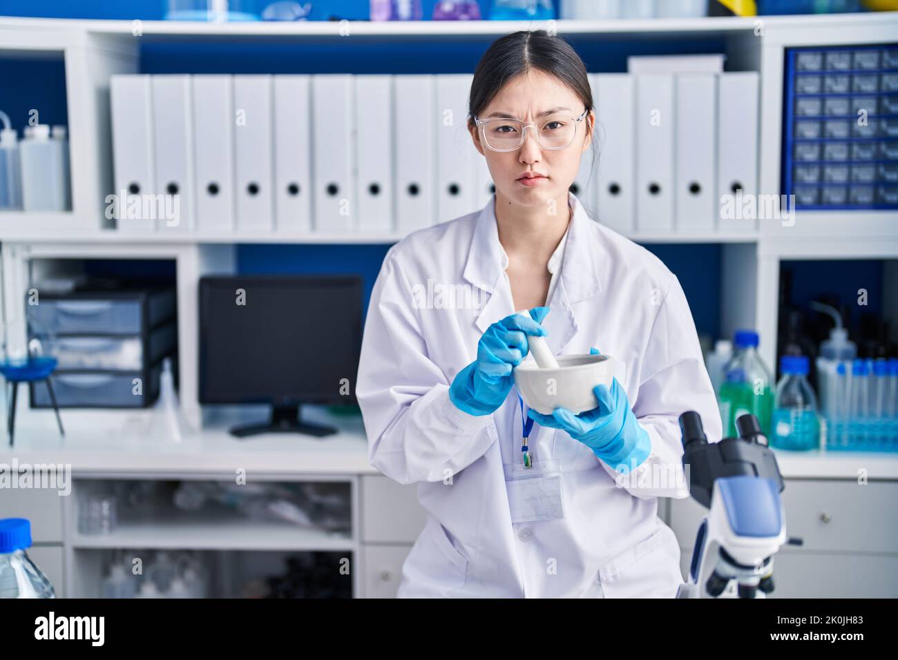 Chinese young woman working at scientist laboratory mixing skeptic and ...