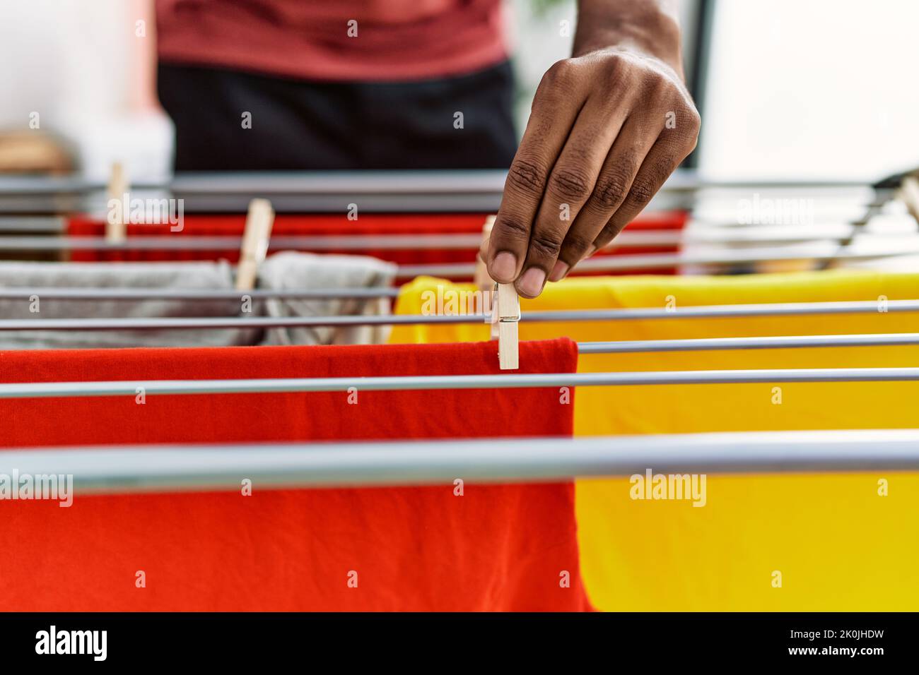 Young african american man hanging clothes at laundry room Stock Photo ...