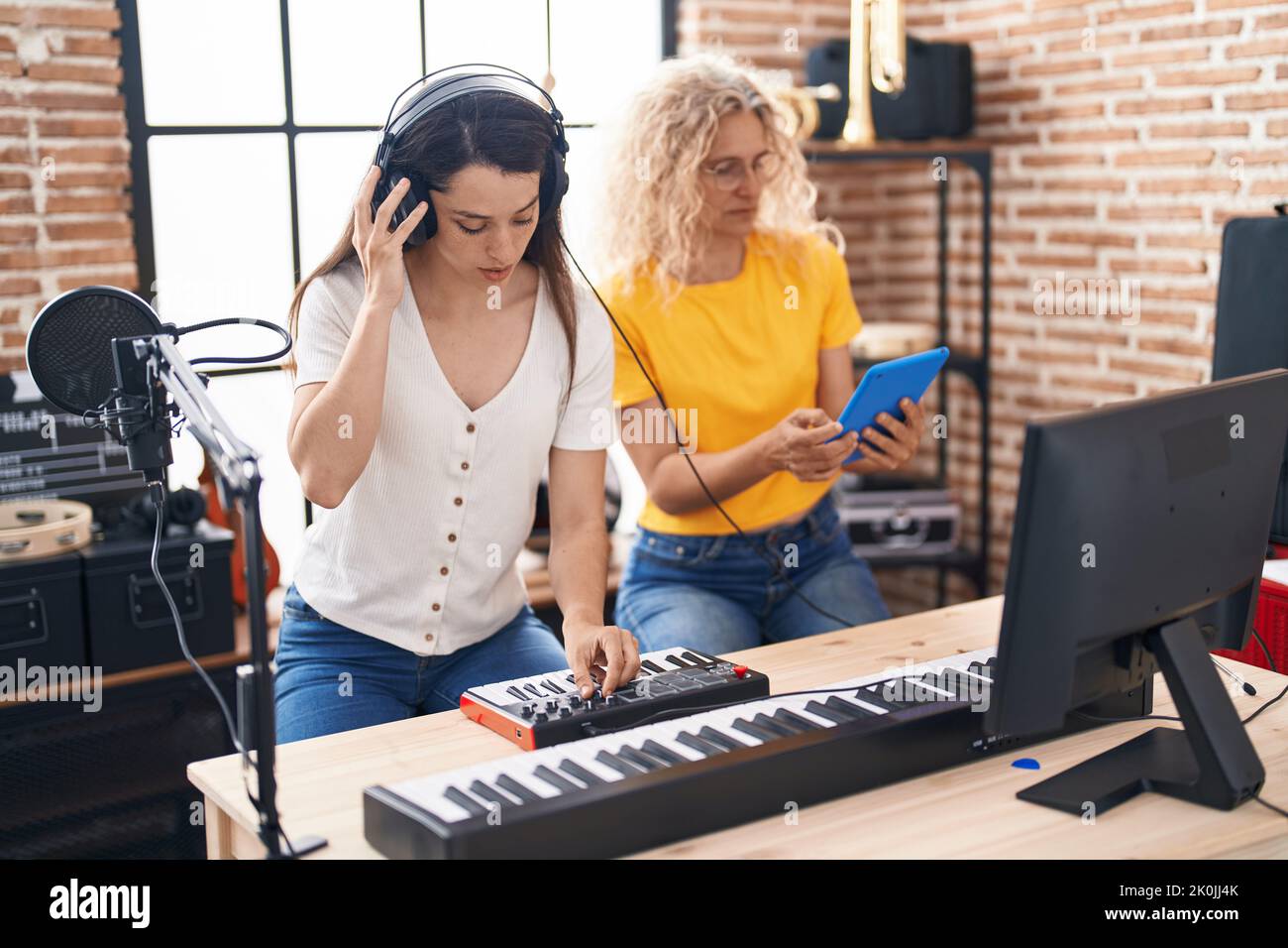 Two women musicians composing song using keyboard and touchpad at music ...