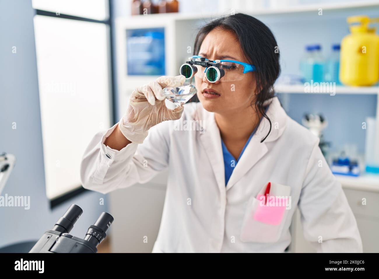 Young chinese woman wearing scientist uniform examining diamond at ...