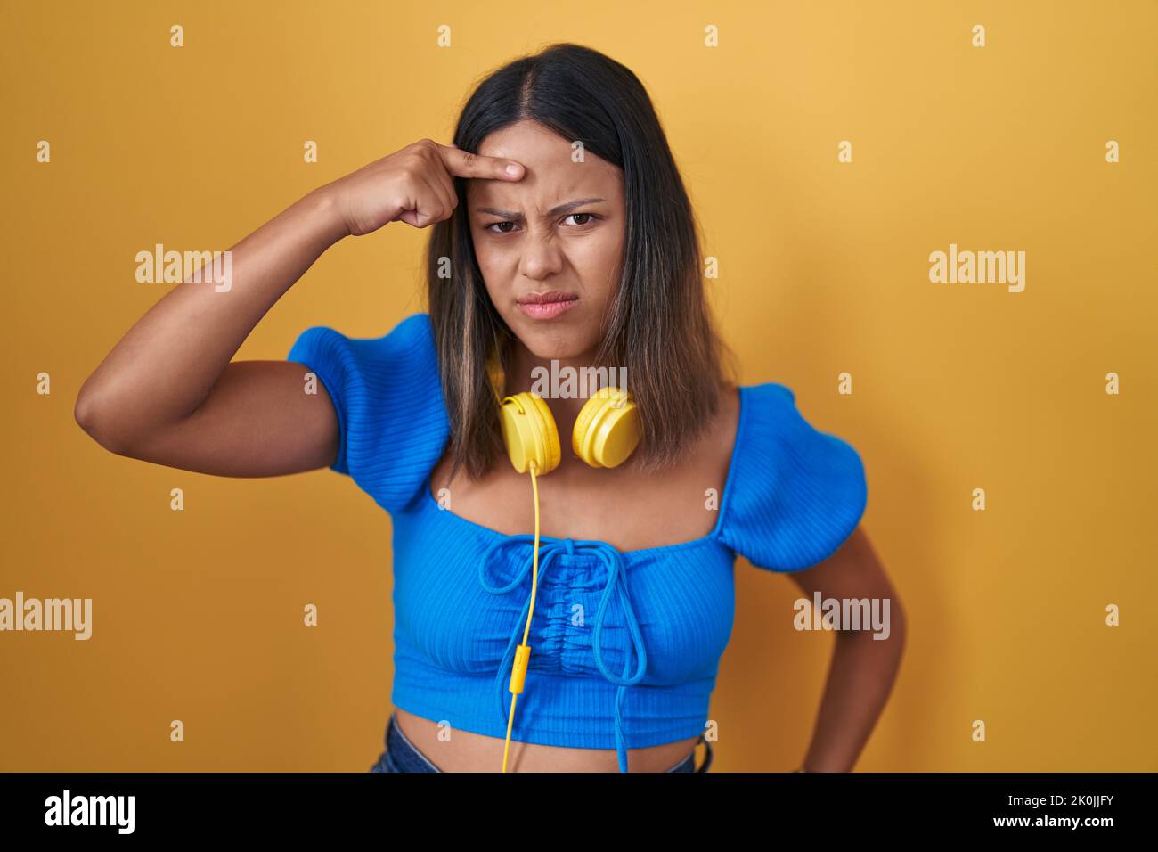 Hispanic young woman standing over yellow background pointing unhappy ...
