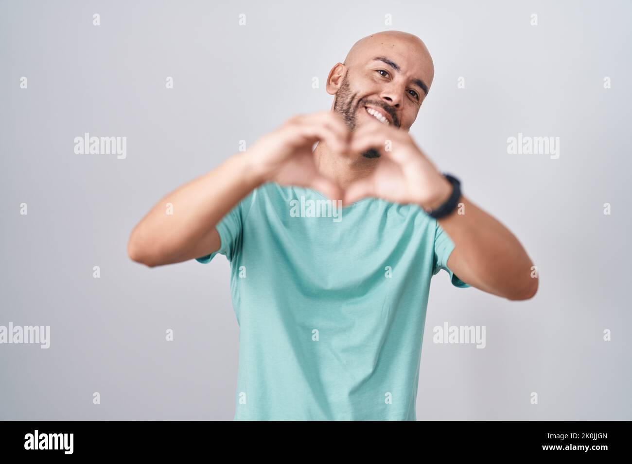 Middle age bald man standing over white background smiling in love ...