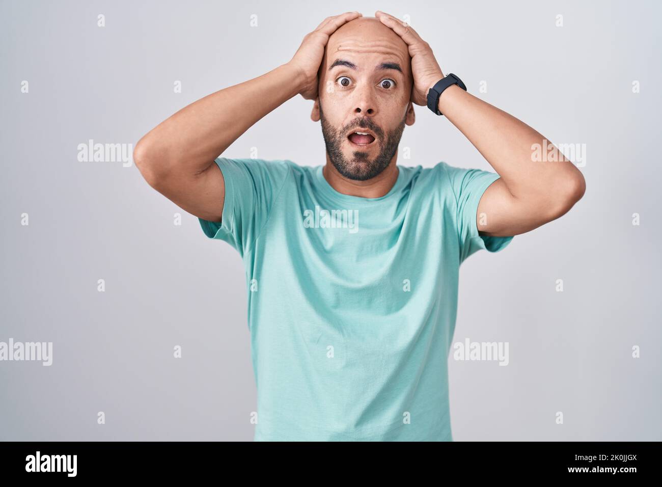 Middle age bald man standing over white background crazy and scared ...