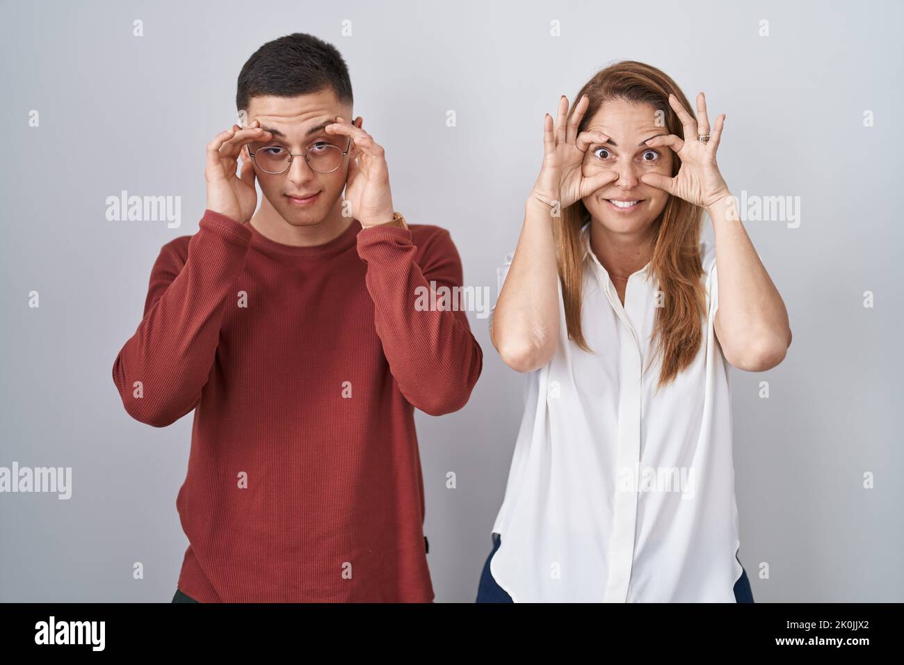 Mother and son standing together over isolated background trying to ...