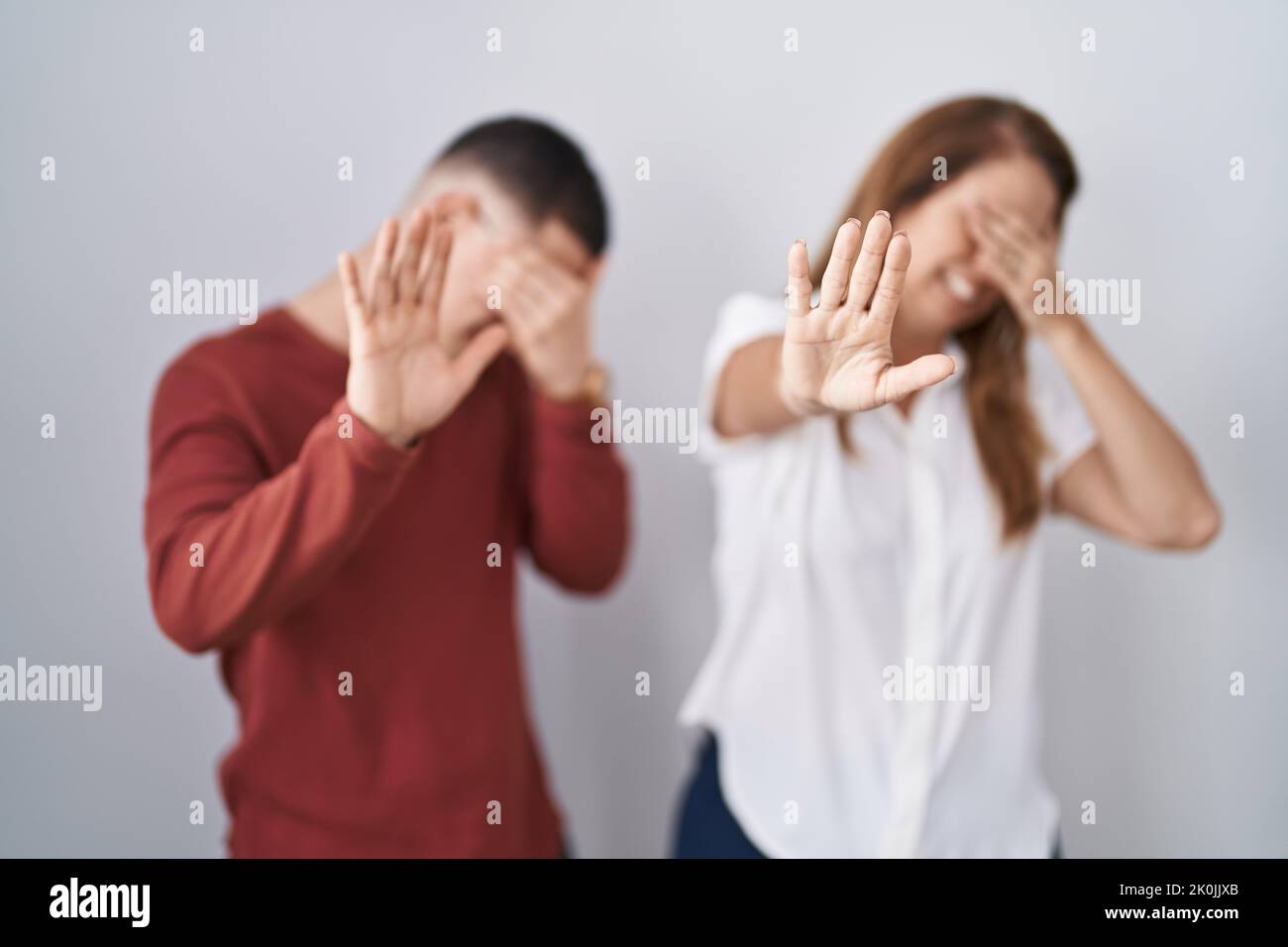 Mother and son standing together over isolated background covering eyes ...