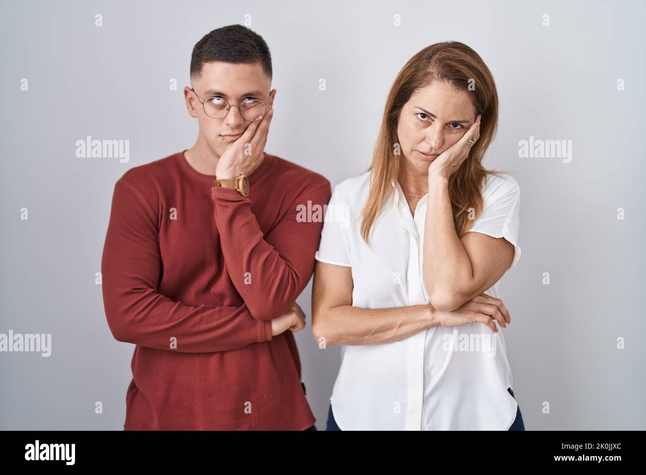 Mother and son standing together over isolated background thinking ...