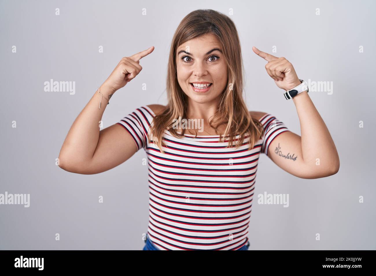 Young hispanic woman standing over isolated background smiling pointing ...