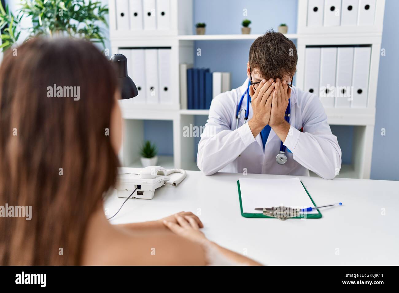 Young doctor with client at medical clinic with sad expression covering ...